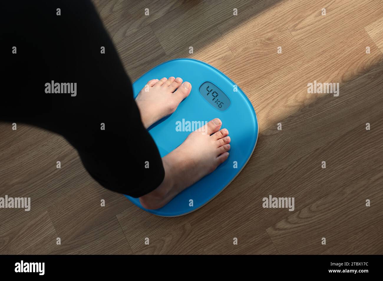 Lower body of a woman standing on a weight scale Stock Photo - Alamy