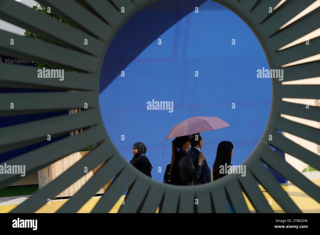 A woman walks with an umbrella to shield herself from the sun during ...