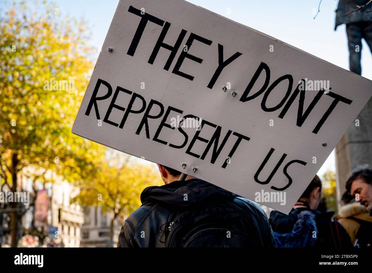 A protester holds a placard reading, "they don't represent us" during ...