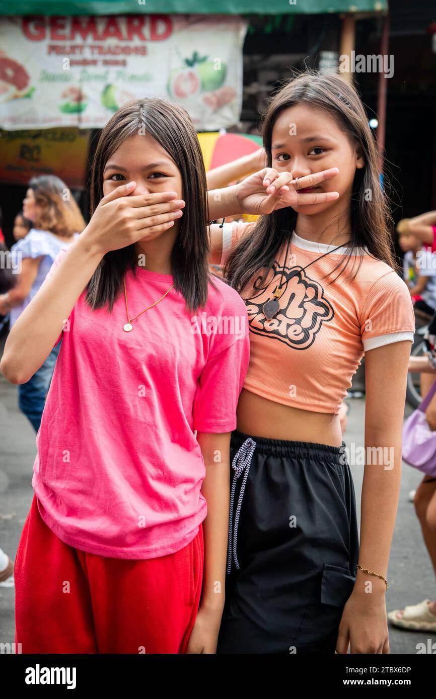 Two Young Filipino Girls Make A Cheeky Pose And Hand Signal During A Religious Festival In 0561