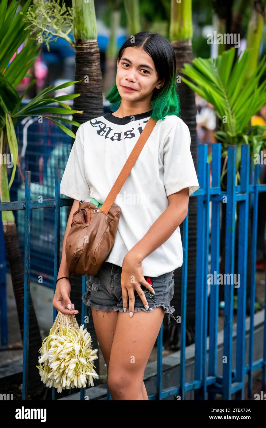 A beautiful young Filipino girl sells flower garlands outside the St ...