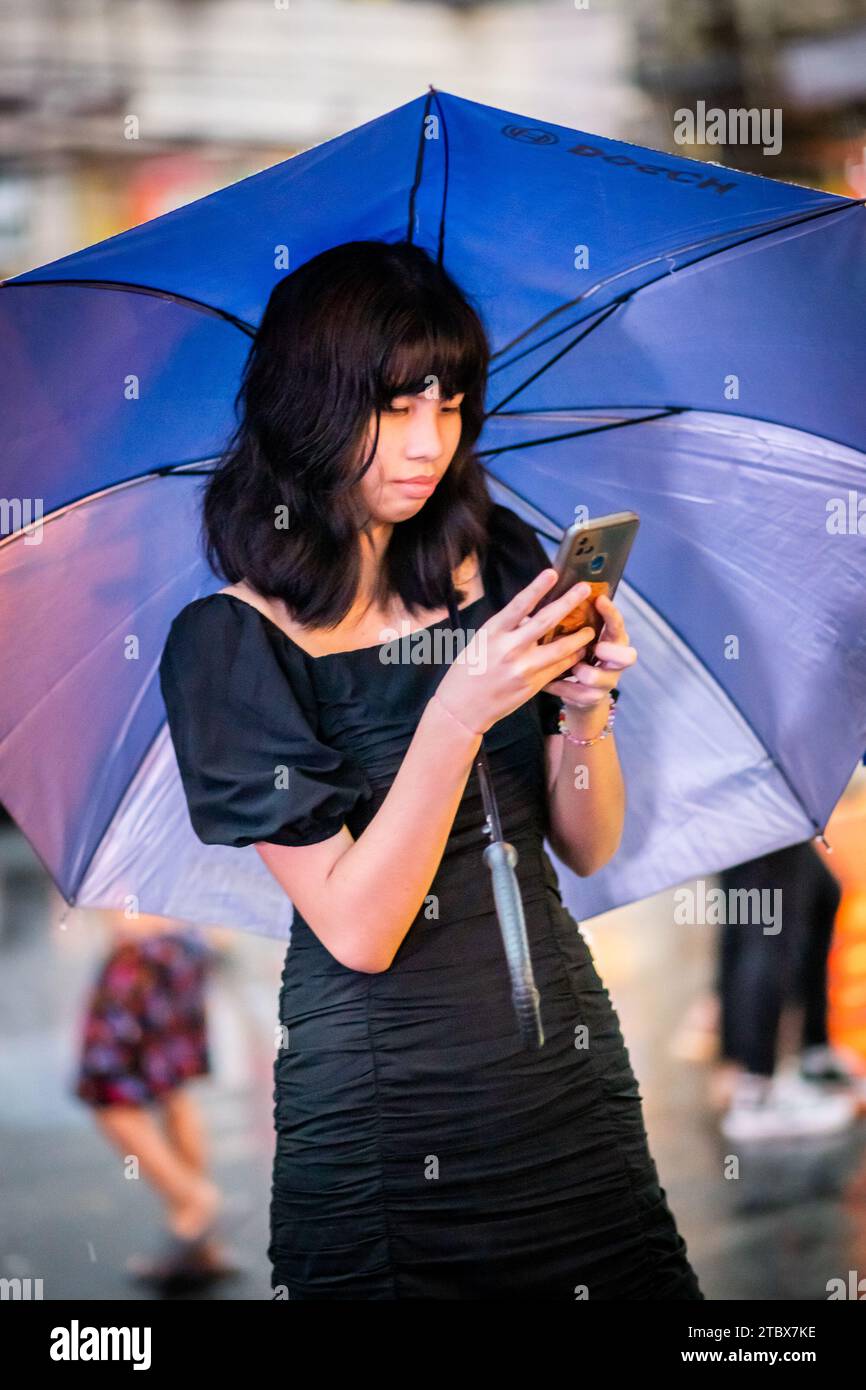A beautiful Filipino girl keeps dry from the rain under an umbrella in ...