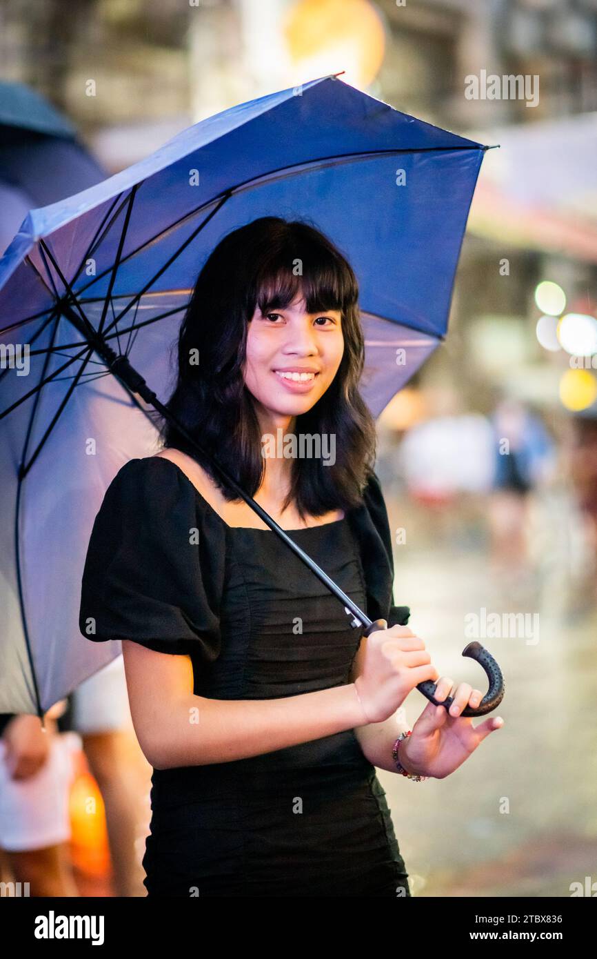 A beautiful Filipino girl keeps dry from the rain under an umbrella in ...