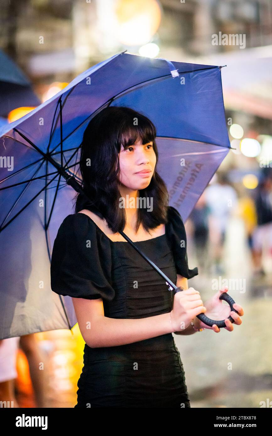 A beautiful Filipino girl keeps dry from the rain under an umbrella in ...