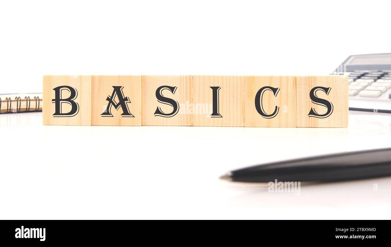 BASICS word word assembled from wooden cubes next to a calculator, pen ...