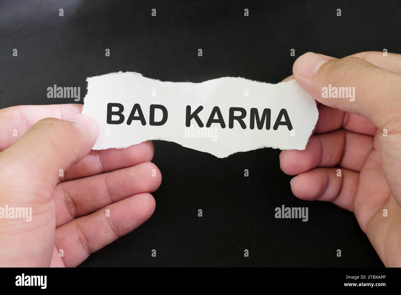 Human hand holding a paper note with word Bad Karma in dark black ...