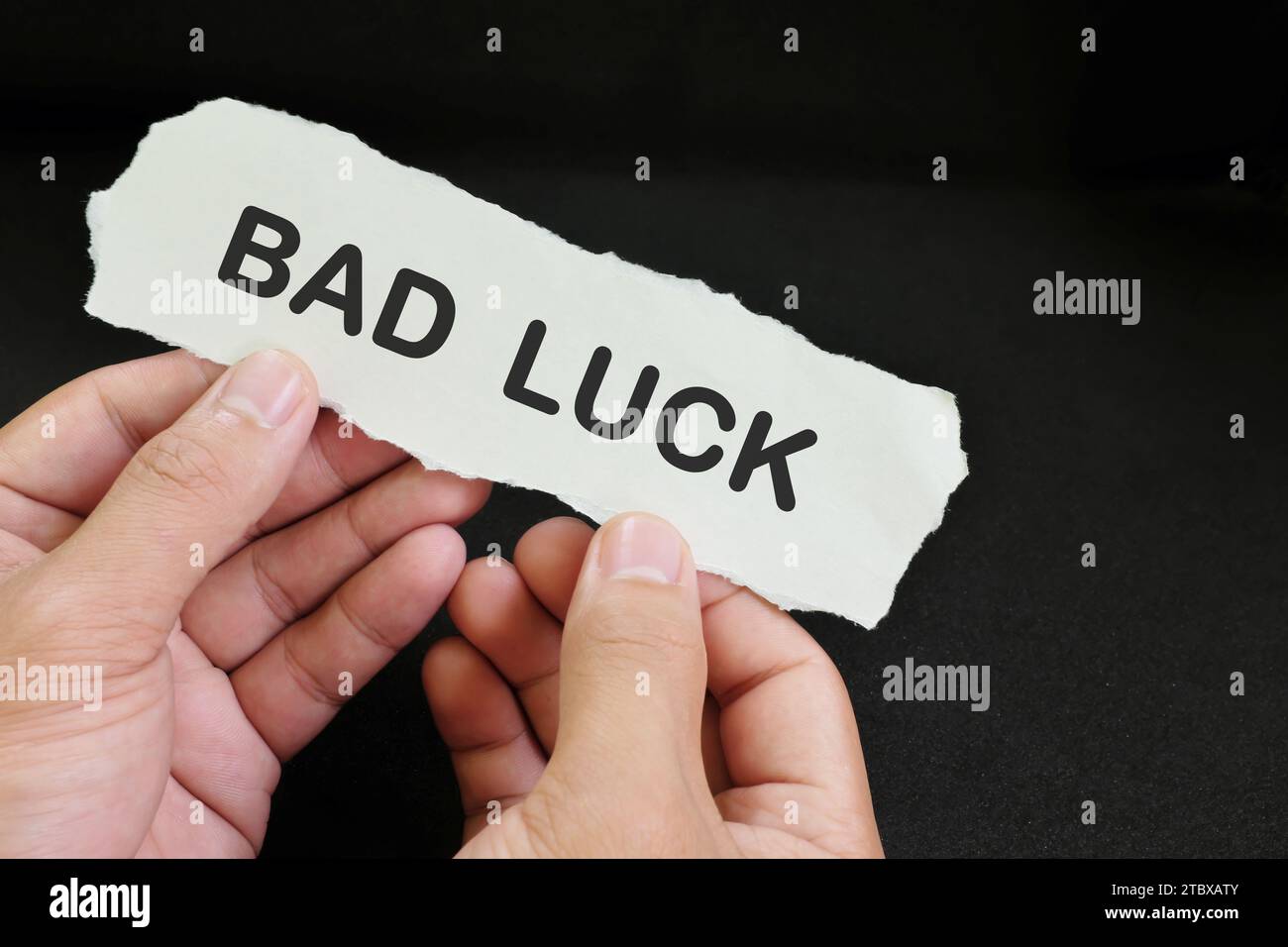 Human hand holding a paper note with word Bad Luck in dark black ...