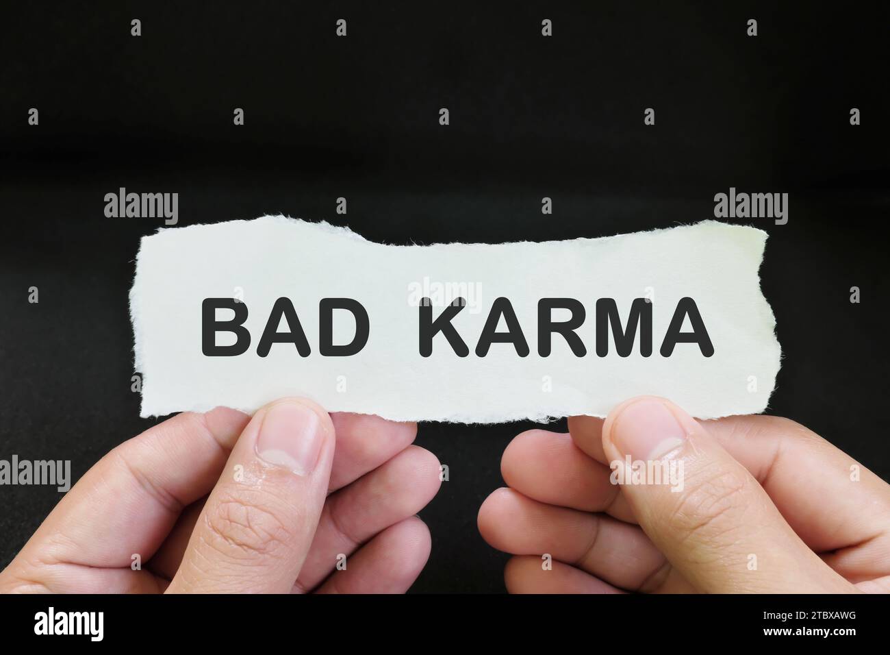 Human hand holding a paper note with word Bad Karma in dark black ...