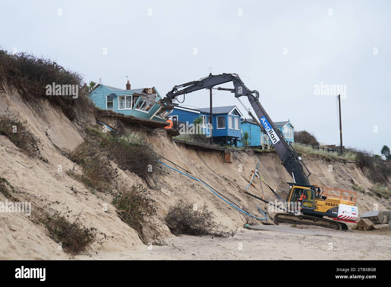 Demolition workers tear down the first of five clifftop homes in the ...