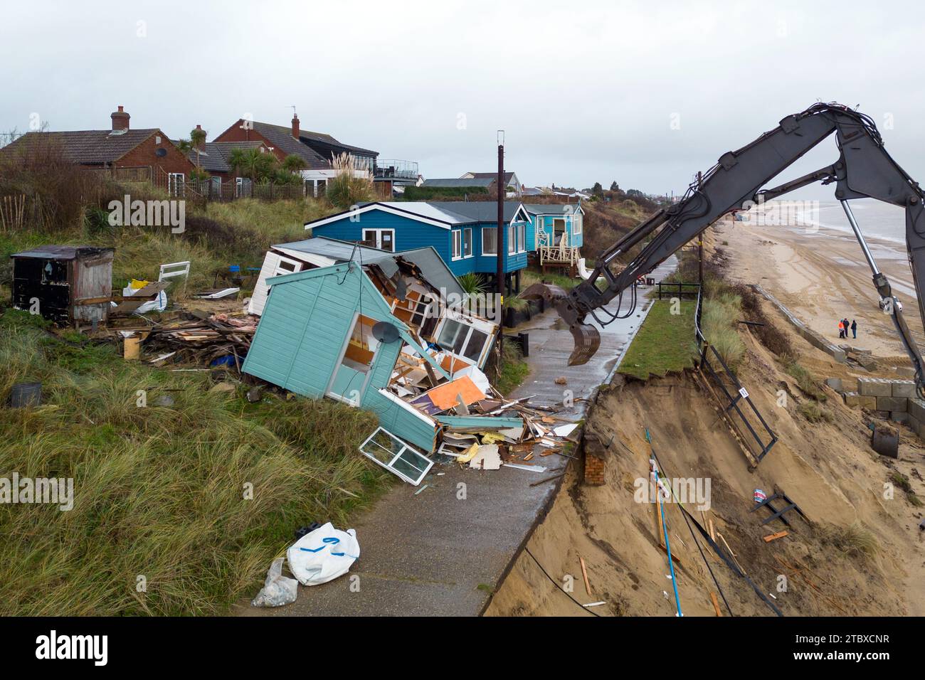 Demolition workers tear down the first of five clifftop homes in the ...