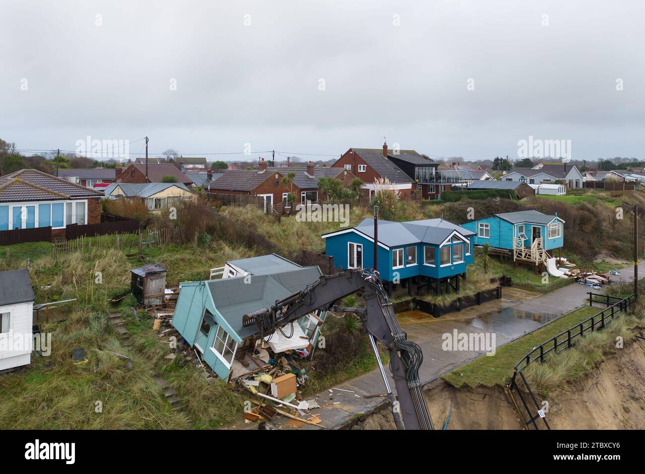 Demolition workers tear down the first of five clifftop homes in the ...