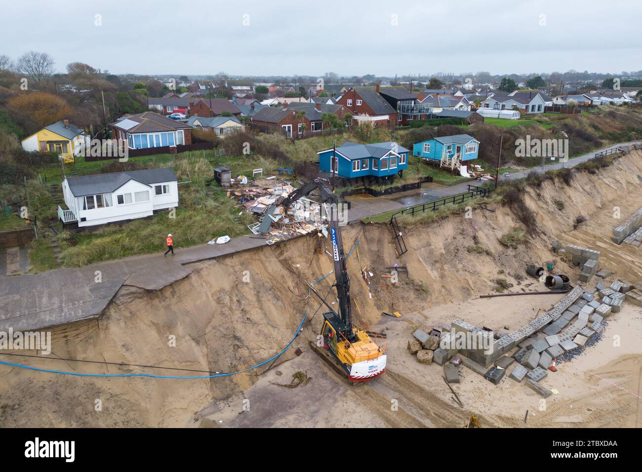 Demolition workers tear down the first of five clifftop homes in the ...
