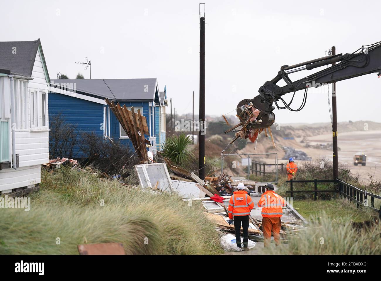 Demolition workers tear down the first of five clifftop homes in the ...
