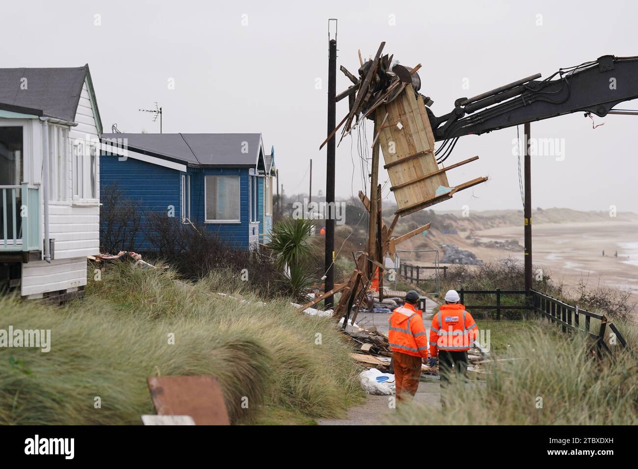 Demolition workers tear down the first of five clifftop homes in the ...
