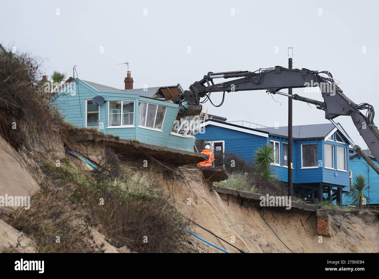 Demolition workers tear down the first of five clifftop homes in the ...