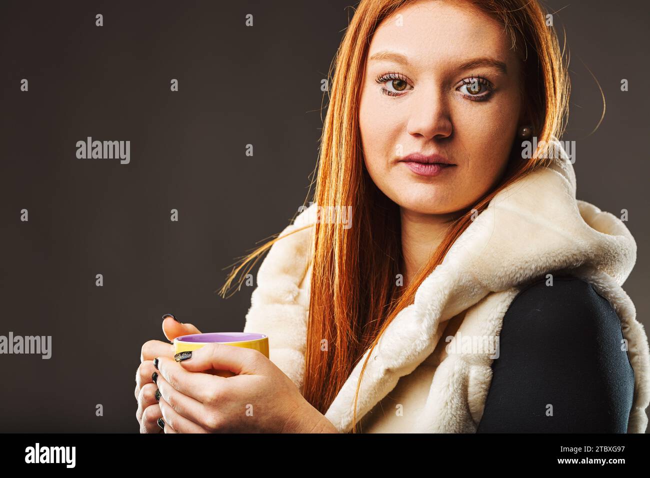 Woman finds comfort in a hot beverage, her attire suggesting a break ...