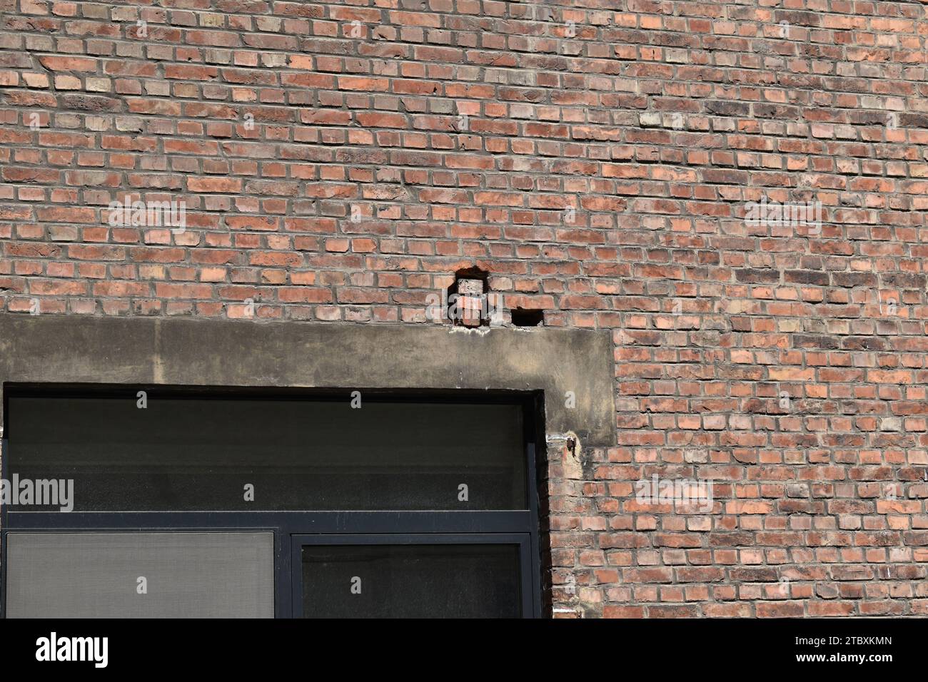 Three red bricks filling a hole in a brick wall above a window Stock ...