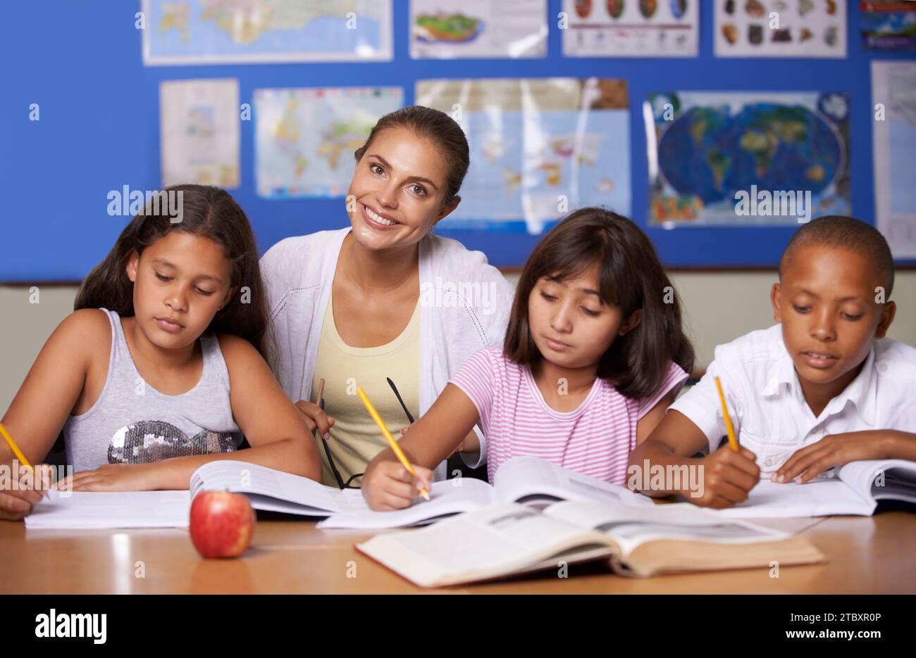 Teacher, portrait and school kids in classroom, writing or learning ...