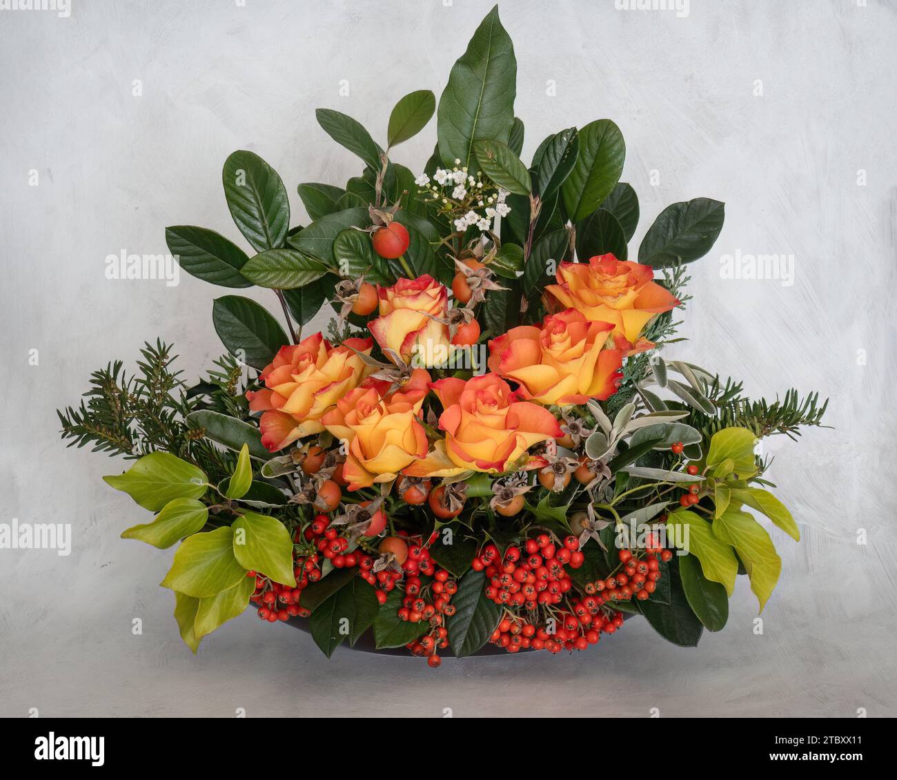 Winter festive floral arrangement. Flame colour roses, berries ...