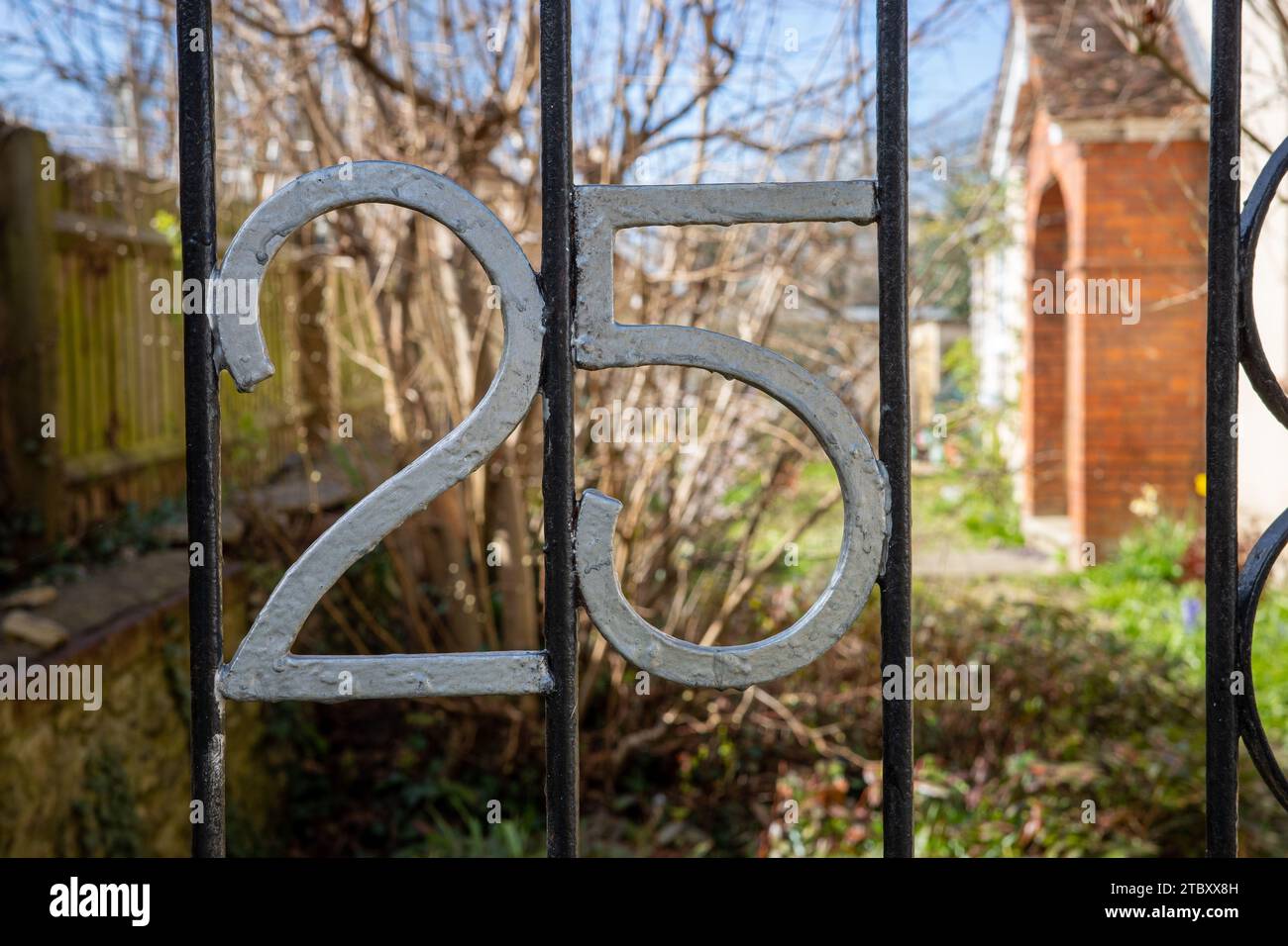 Number 25 on a wrought iron gate with a garden behind Stock Photo - Alamy