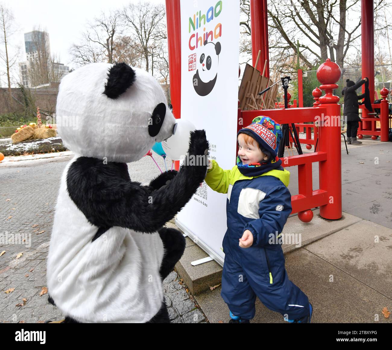 Berlin, Germany. 8th Dec, 2023. A child gives a high-five to a staff member in giant panda ...