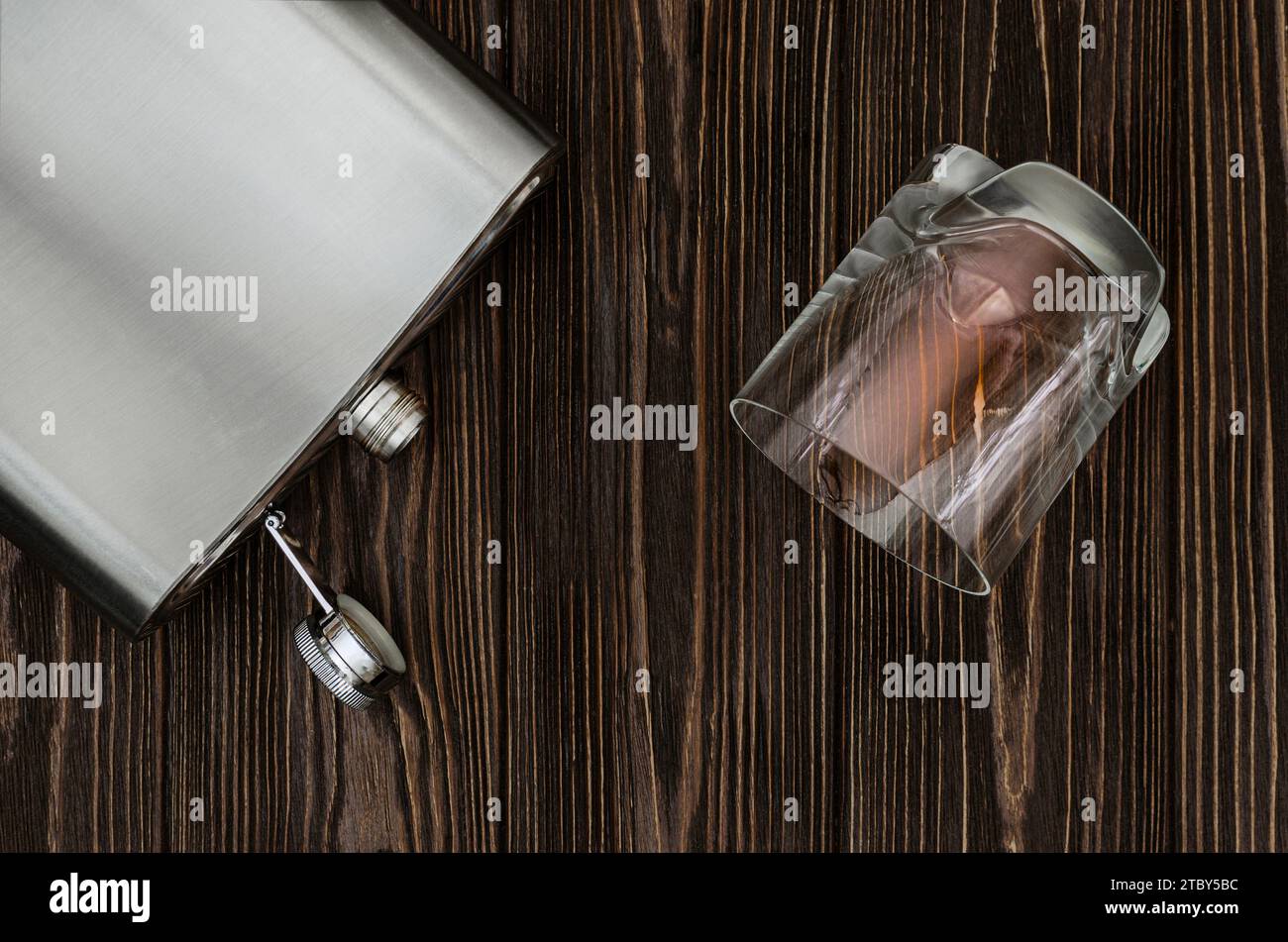 The photograph is a flat arrangement of a flask and a glass on a wooden ...