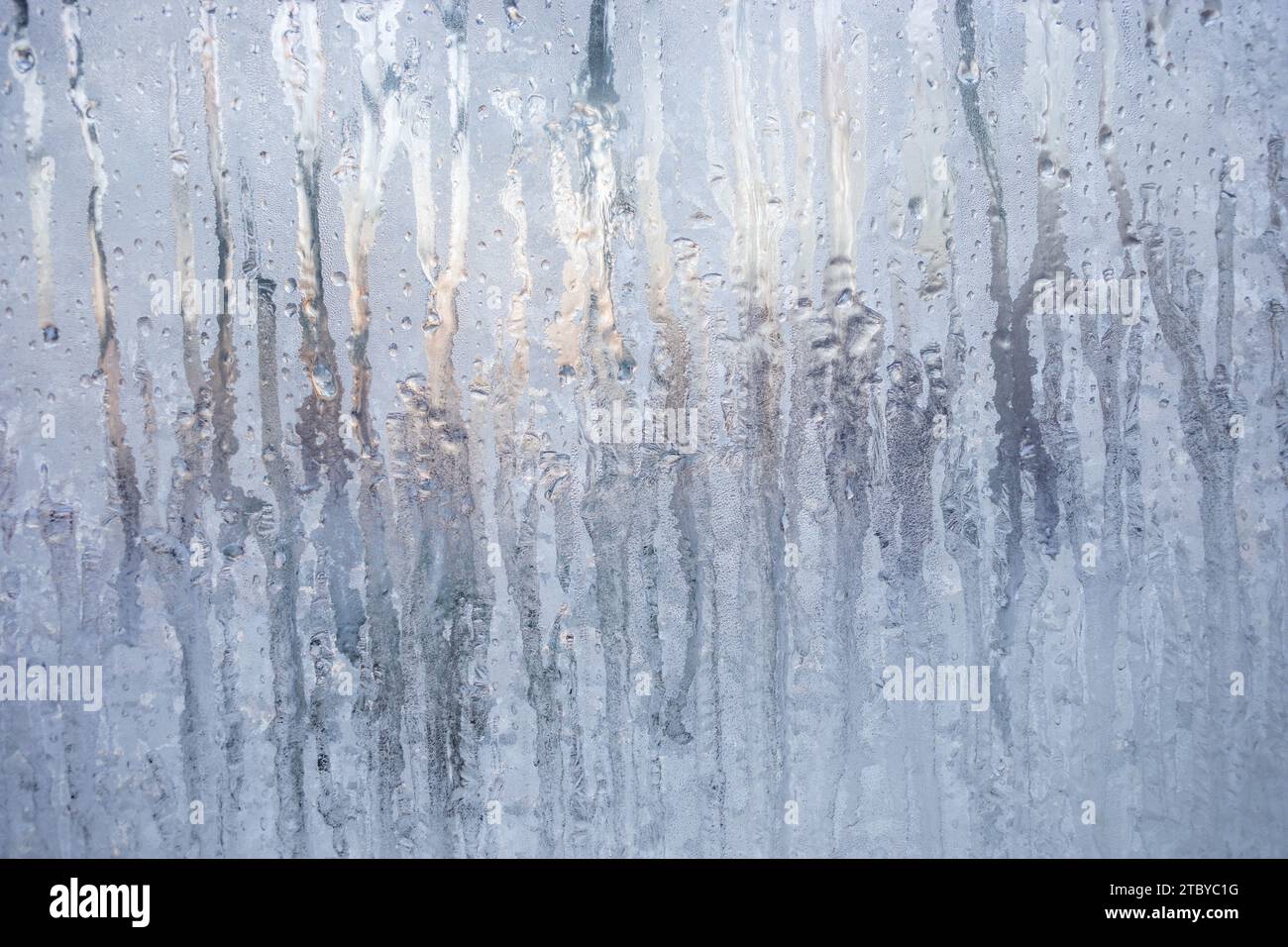 Frozen vertical water streaks and drops on window. Melting frosty ...