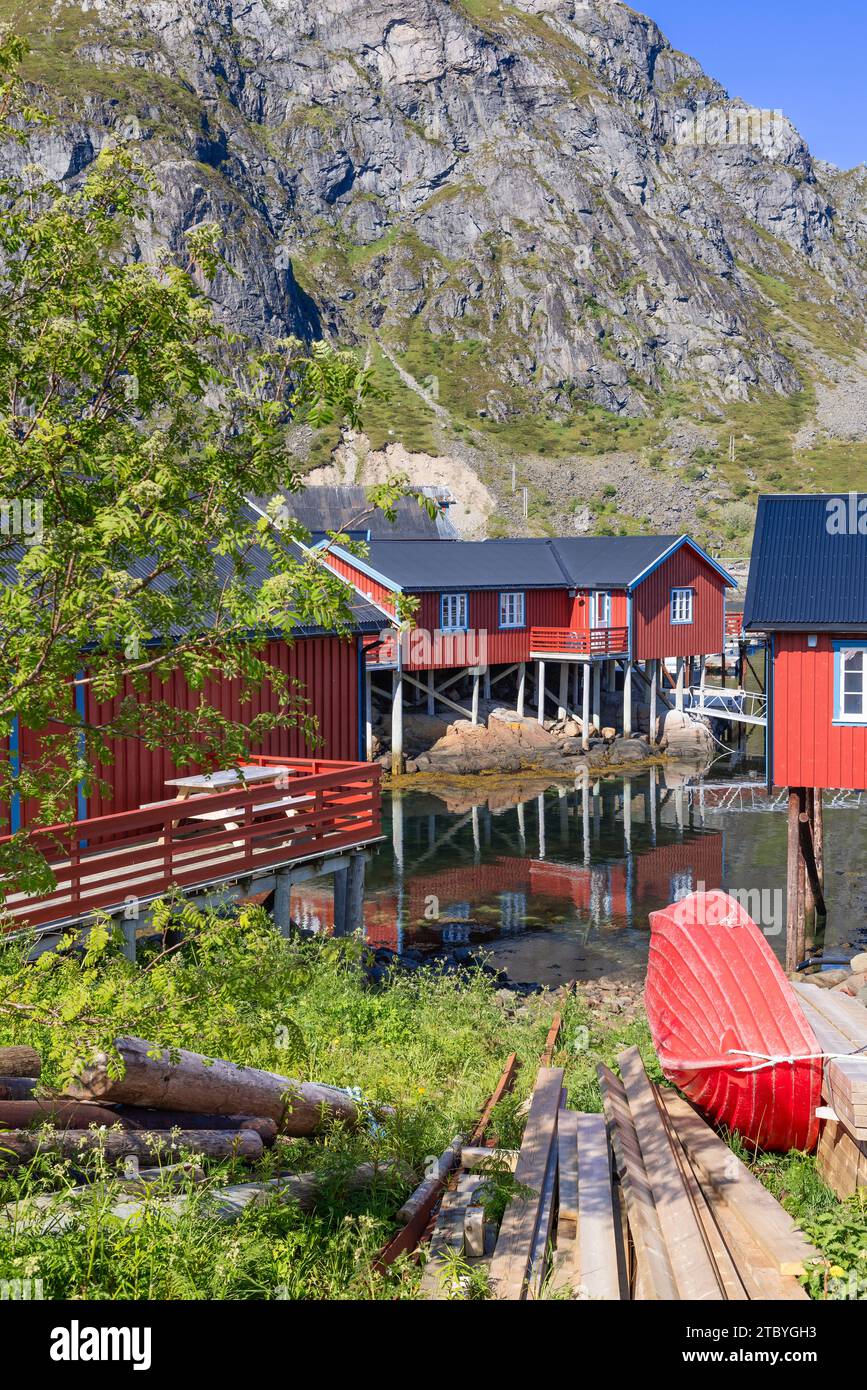 Vertical photo capturing traditional red Rorbu fishing cabins on stilts ...