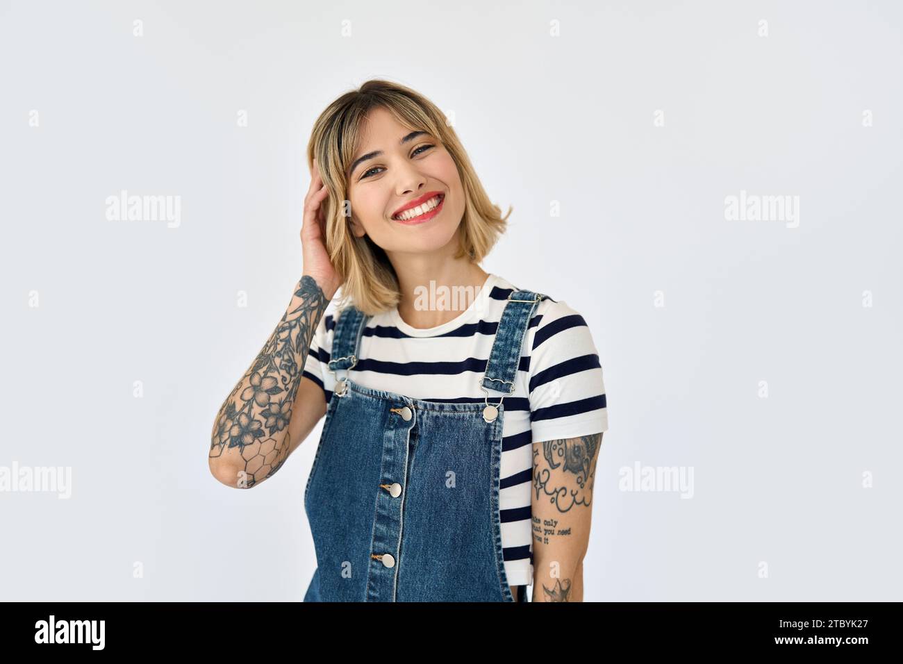 Happy gen z blonde young woman with tattoos standing isolated on white ...