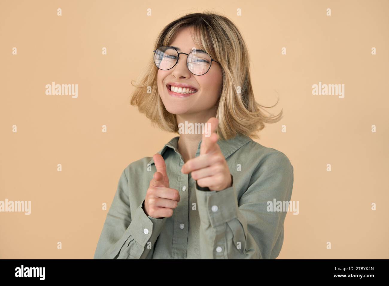 Happy gen z blonde young woman wearing glasses pointing at camera ...