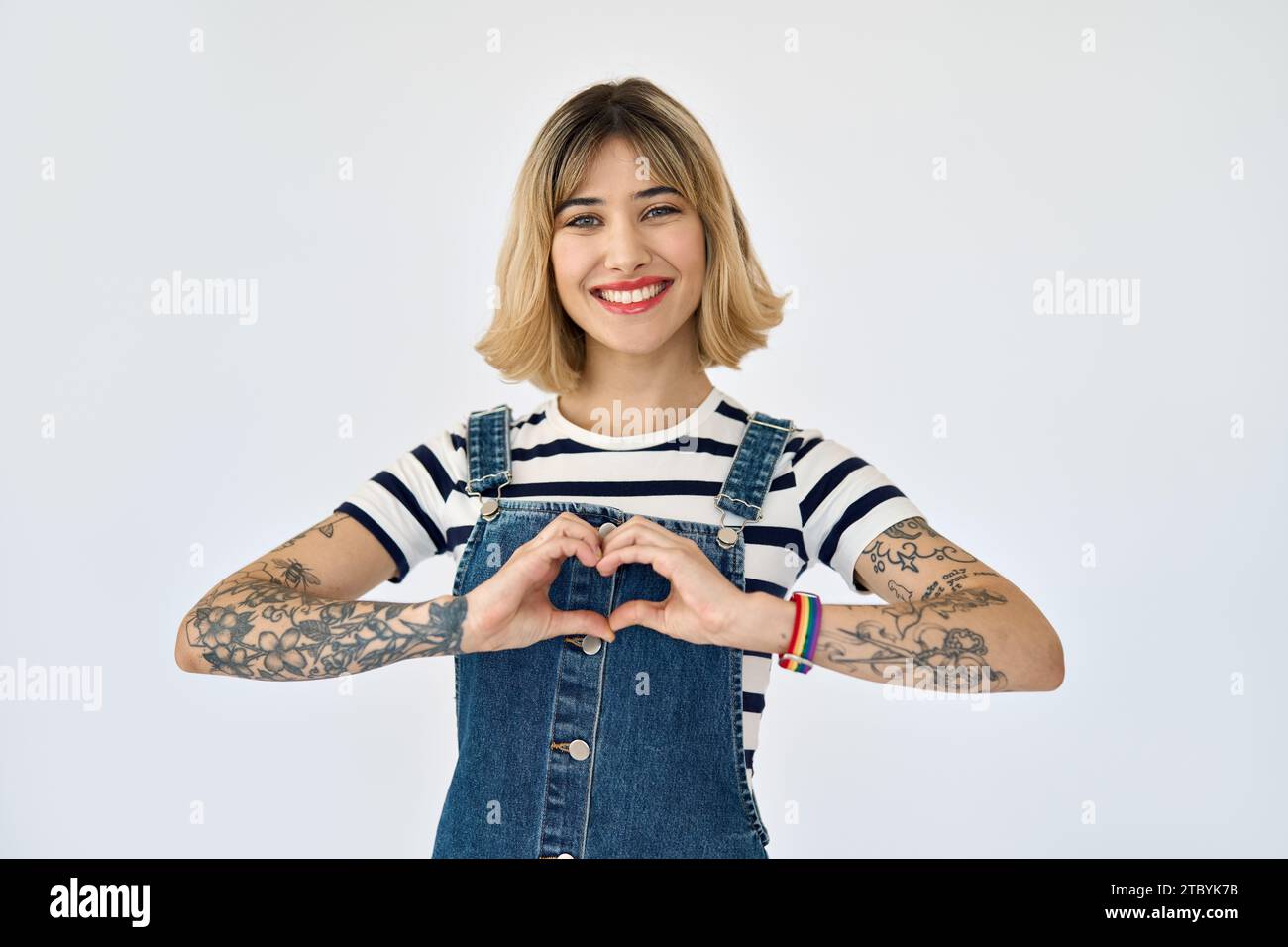 Happy gen z young woman with tattoos rainbow bracelet showing heart ...