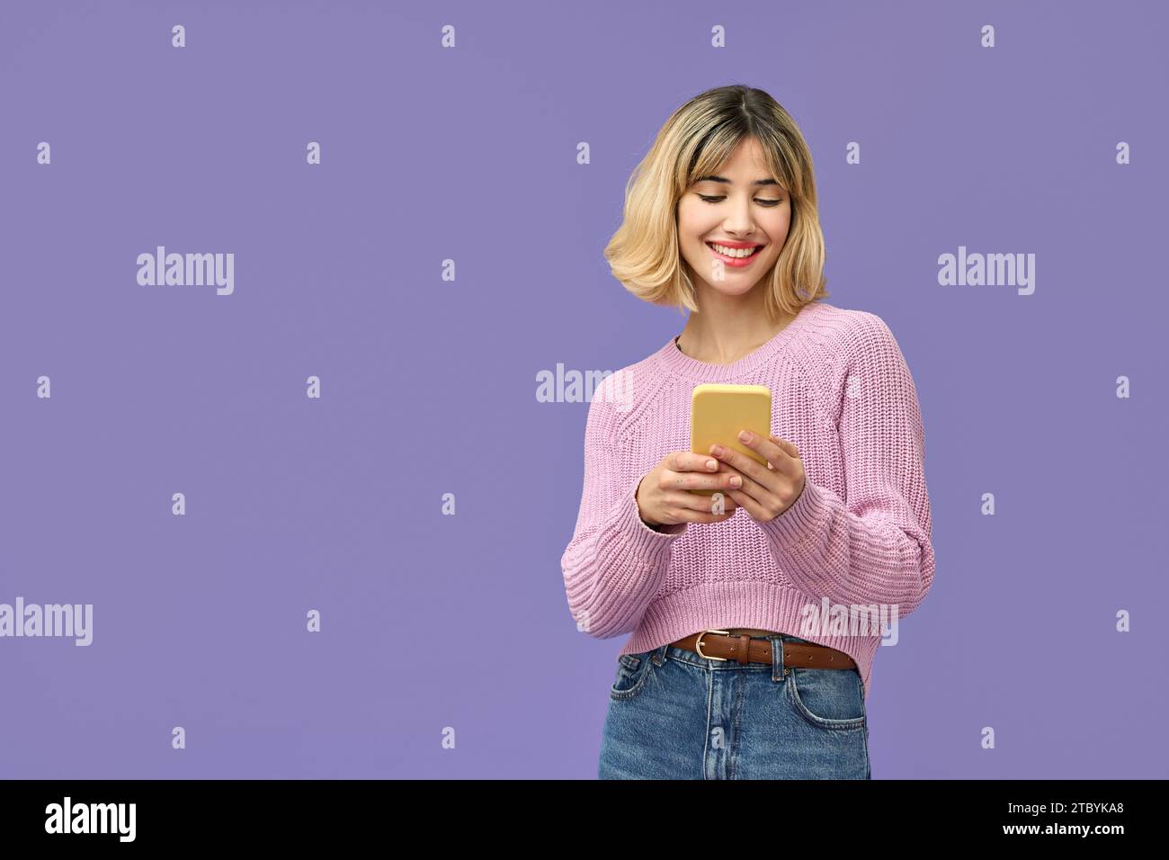 Happy pretty gen z blonde girl using mobile phone isolated on purple ...