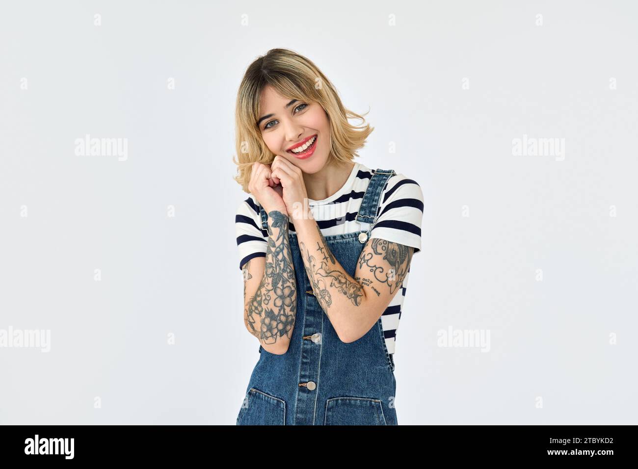 Happy gen z blonde stylish girl with tattoo standing isolated on white ...