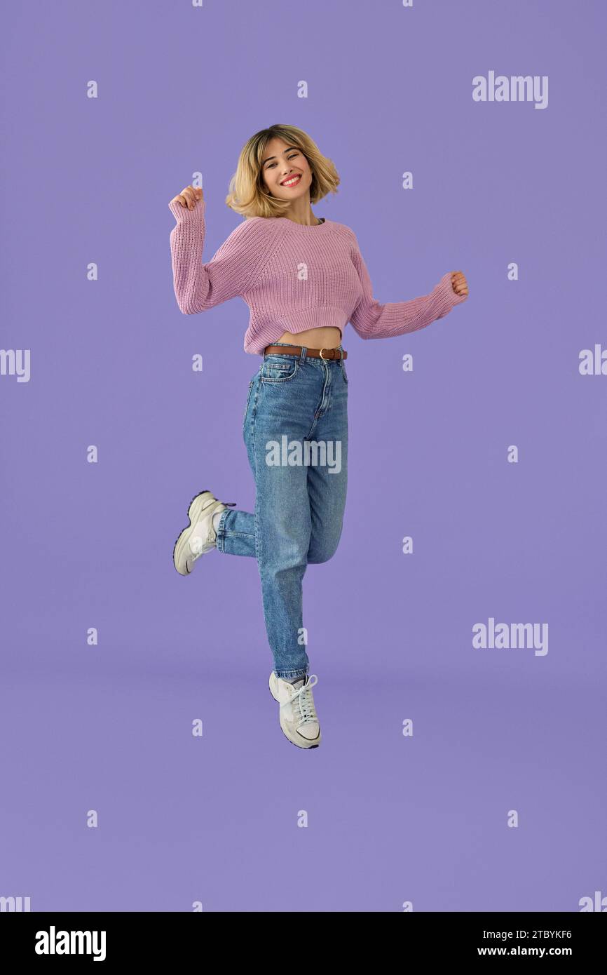 Joyful generation z blonde girl dancing jumping isolated on purple ...