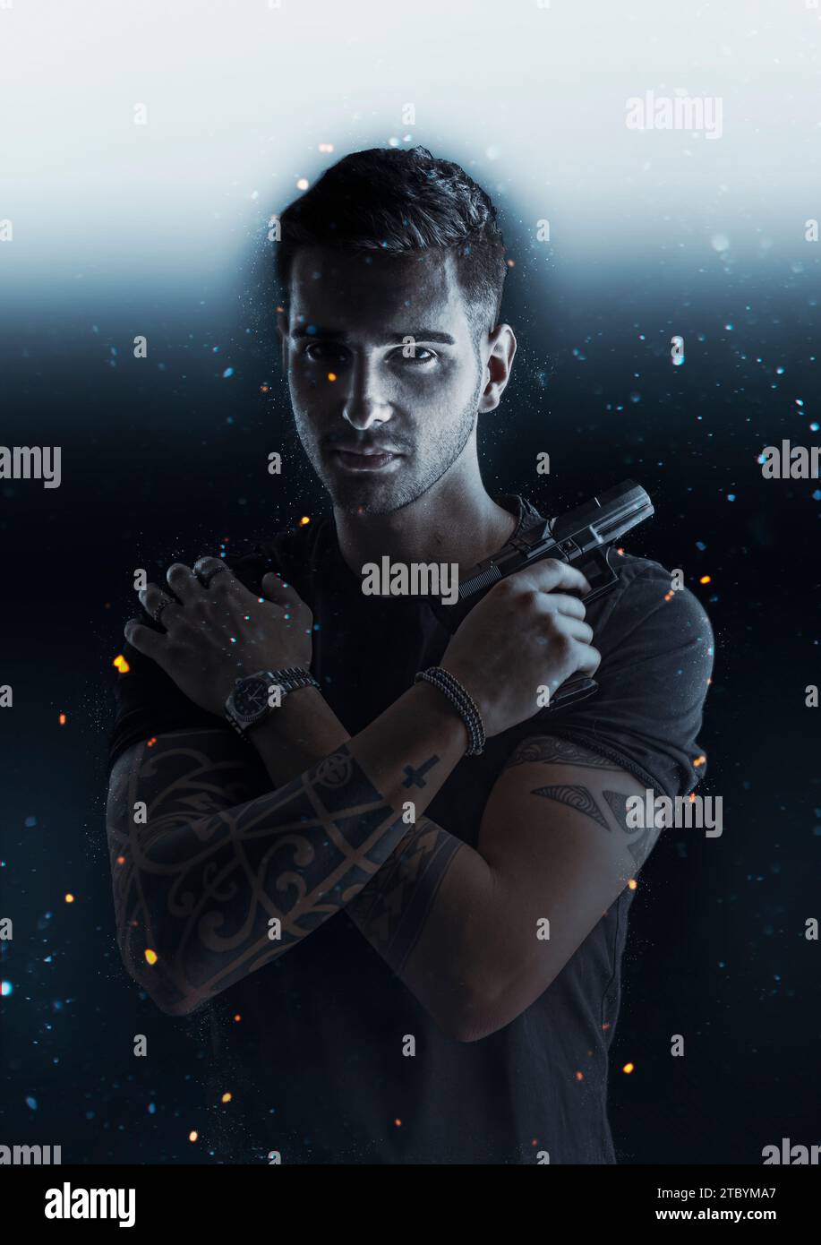 A man with a tattoo on his arm, holding a gun in his hand with shining ...