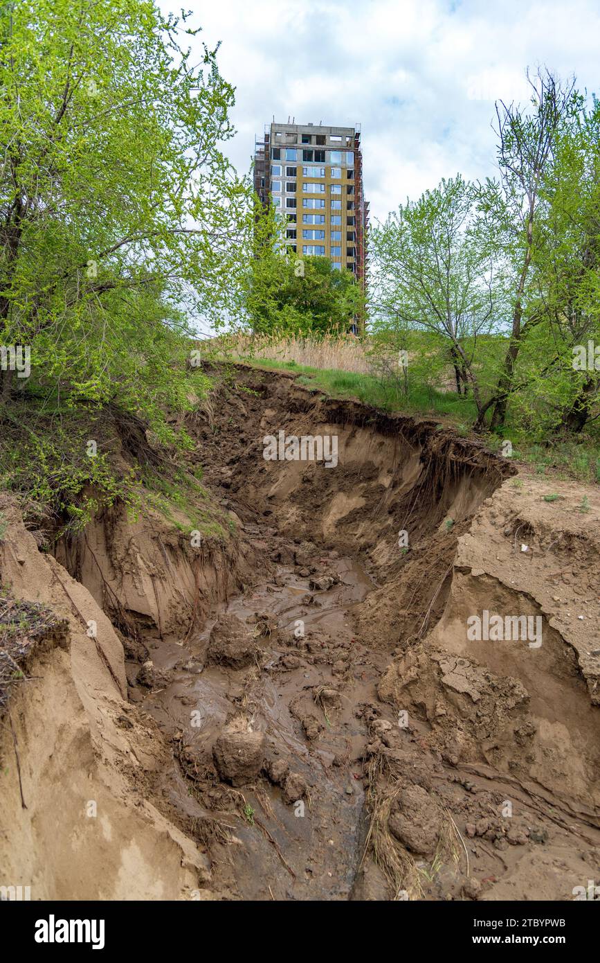 A landslide erodes the slope next to a multi-storey residential ...