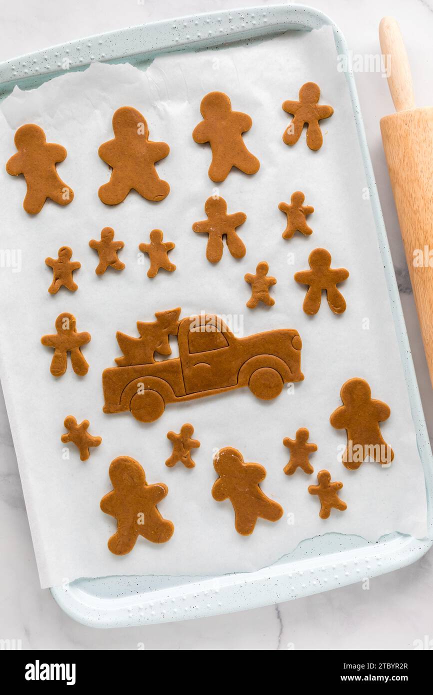 Shapes of unbaked gingerbread cookie dough on a parchment lined tray ...