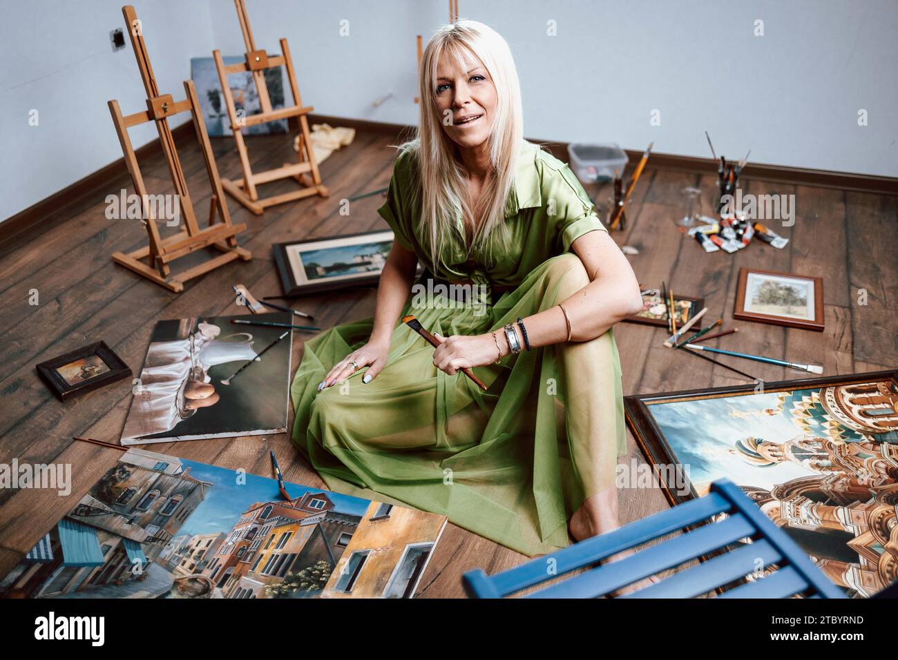 Young blonde woman painter, surrounded by her artwork Stock Photo - Alamy