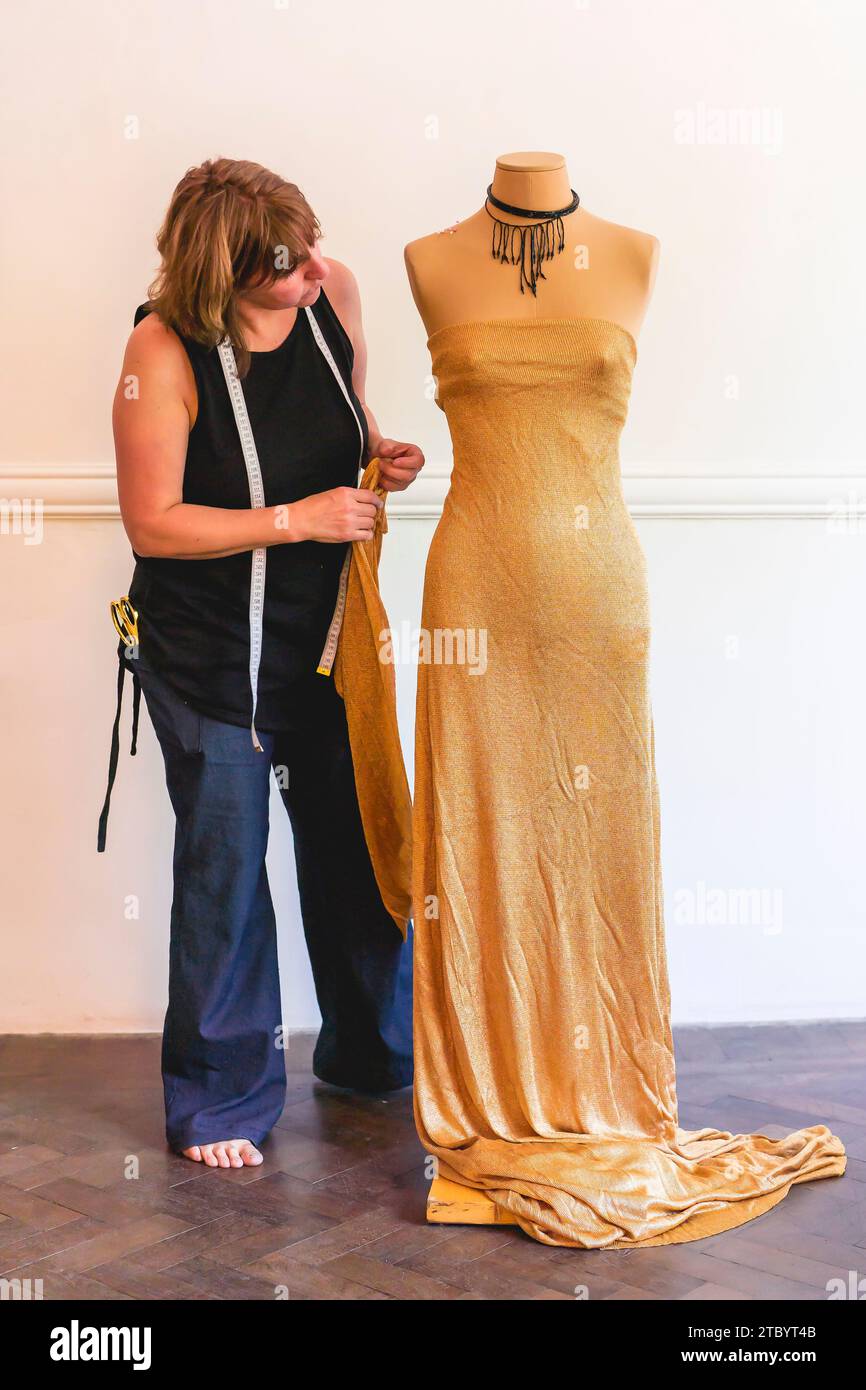 A fashion designer is pinning cut out pieces of fabric to mannequin ...