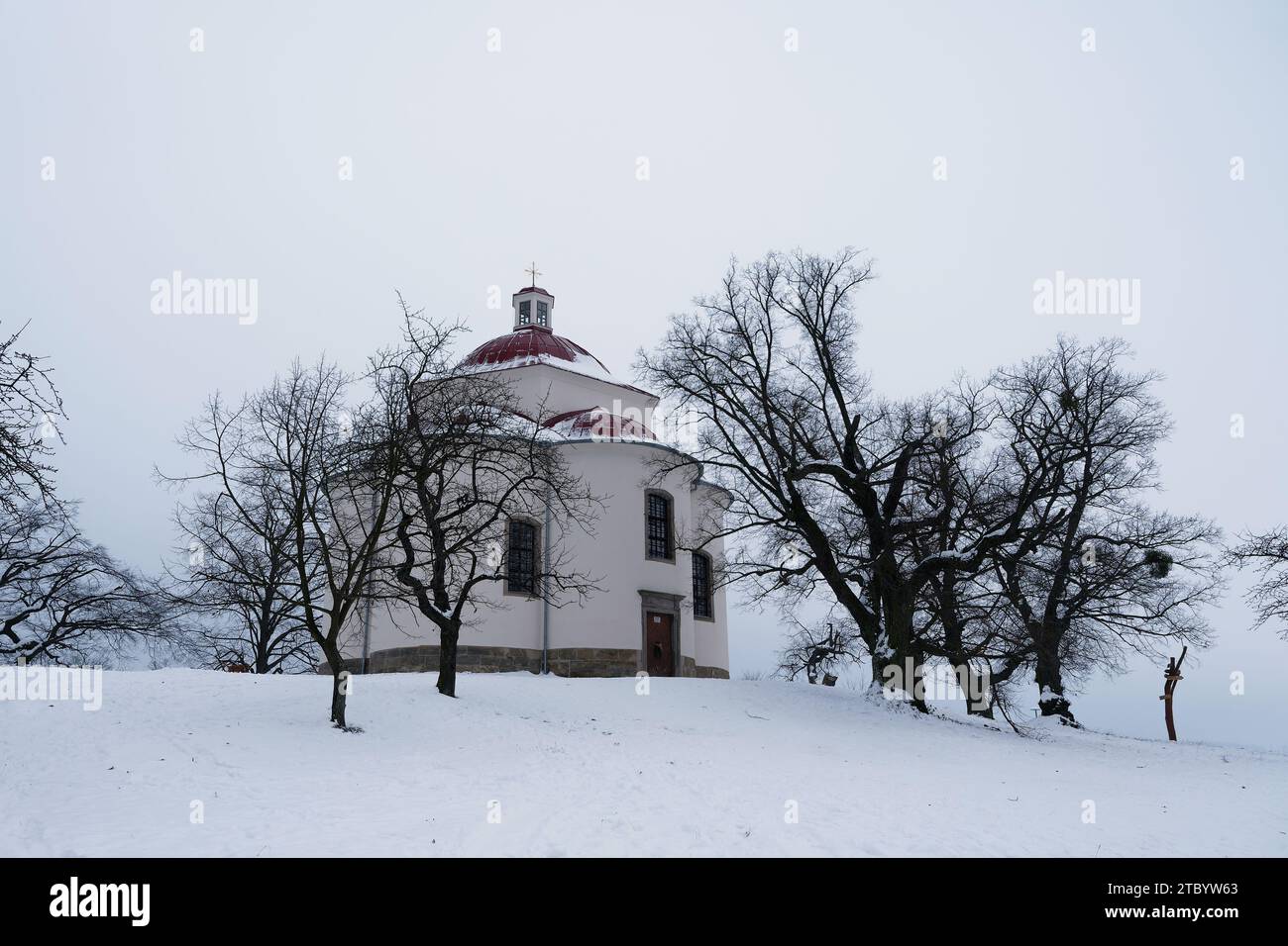A beautiful chapel on a hill with trees and snow. Landscape with nature ...