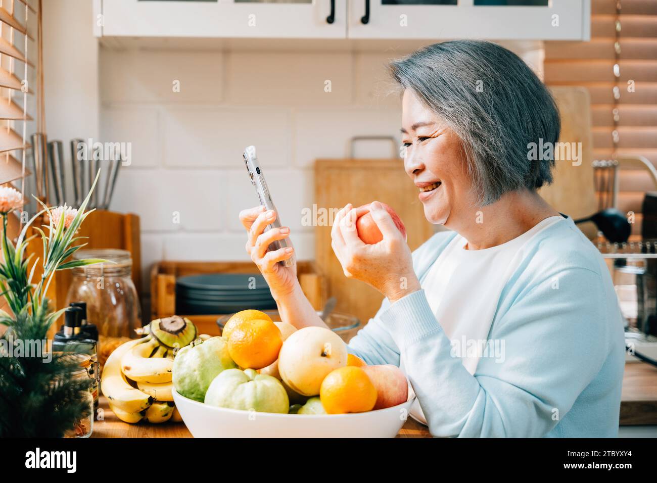 A grandmother, an old woman, is having breakfast in the kitchen. She's ...