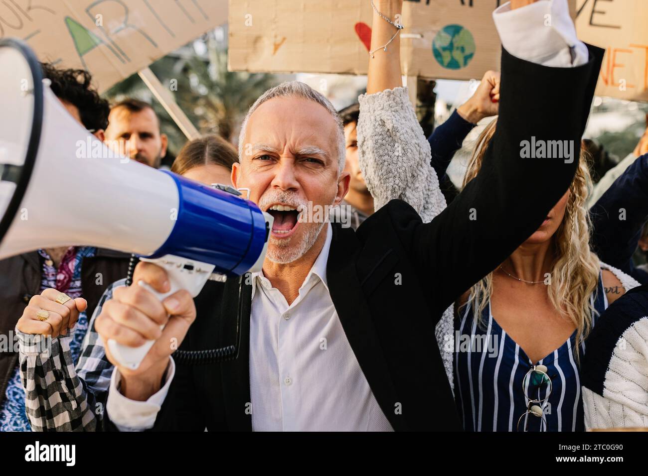 Senior activist man with a megaphone leading protest against climate ...