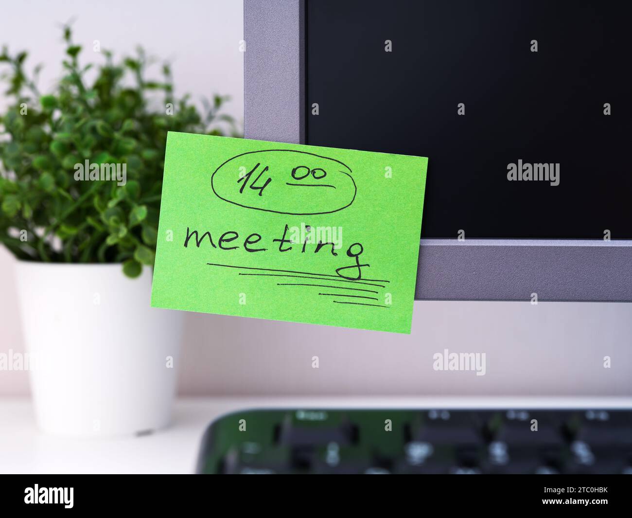 A green paper notes with the reminder 14-00 Meeting on it sticked on to ...