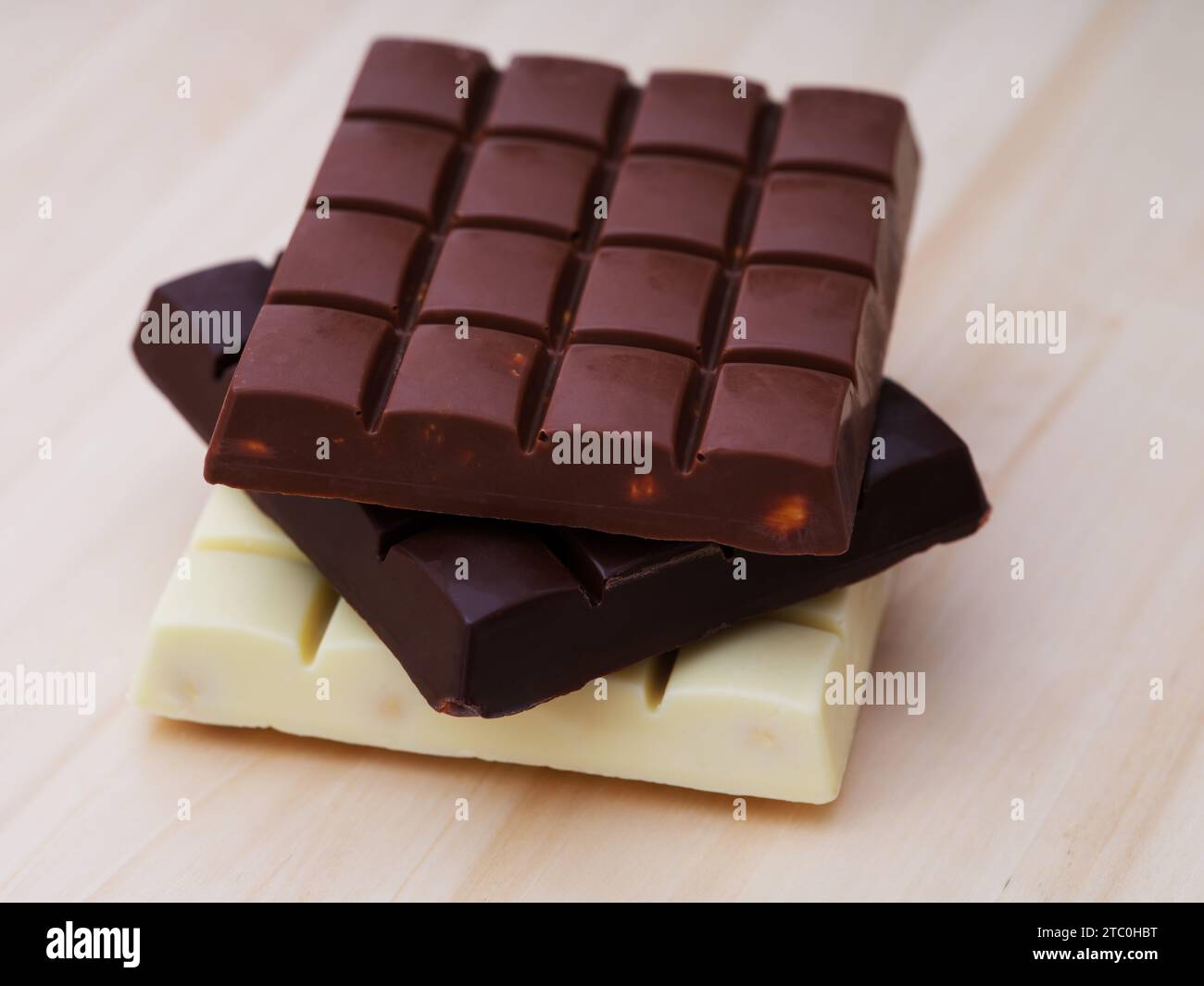 Milk, dark and white chocolate bars in stack on a wooden background ...