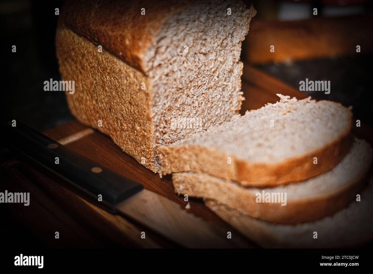 Brown bread on the chopping board being sliced Stock Photo - Alamy