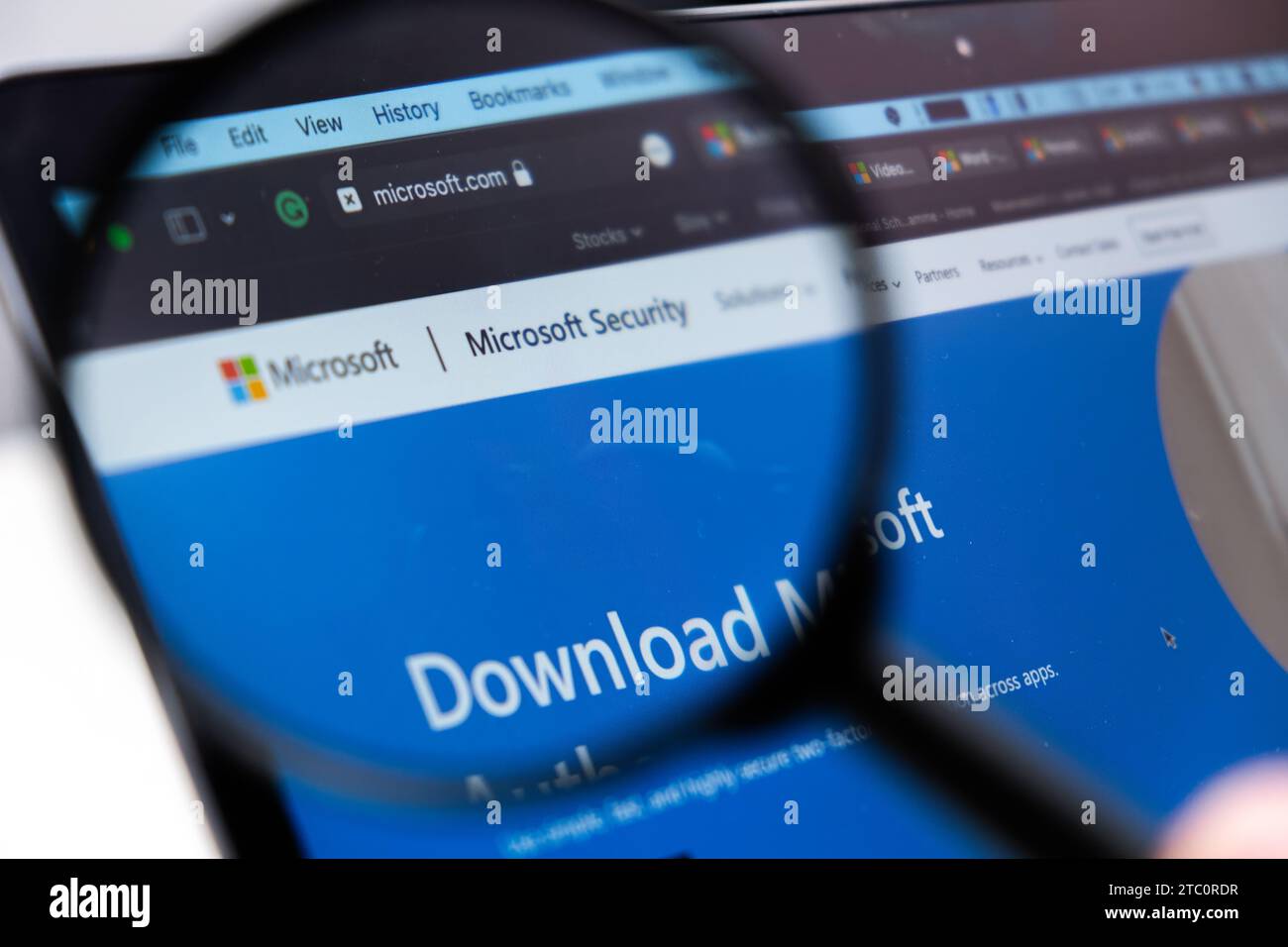 Microsoft Security logo enlarged through a magnifying glass on a laptop ...