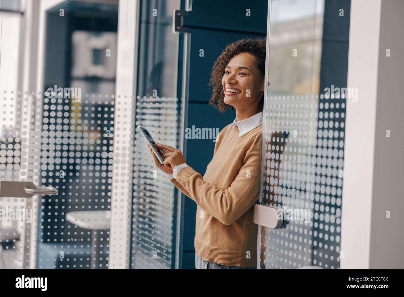 Positive business woman is using phone sitting in office during break ...