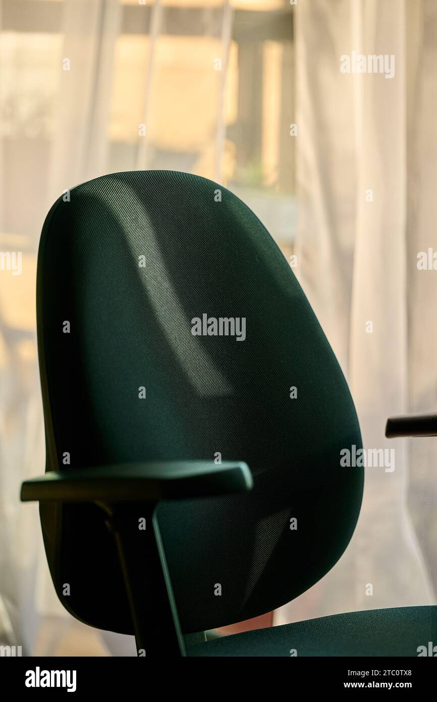 Empty black office chair with armrest with sunlight falling across the ...
