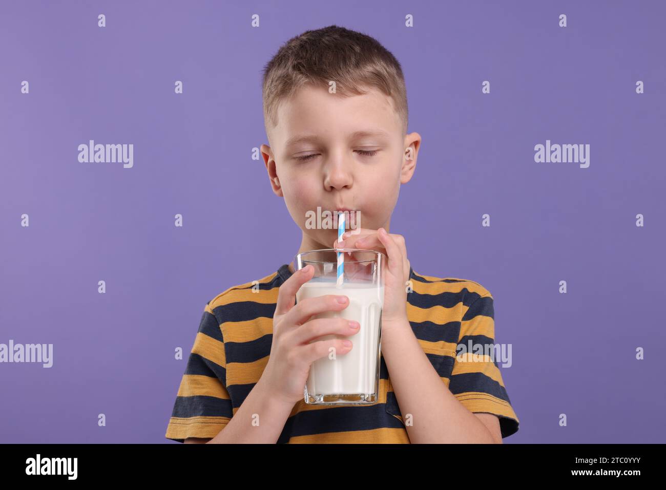 Cute boy drinking fresh milk from glass on violet background Stock ...