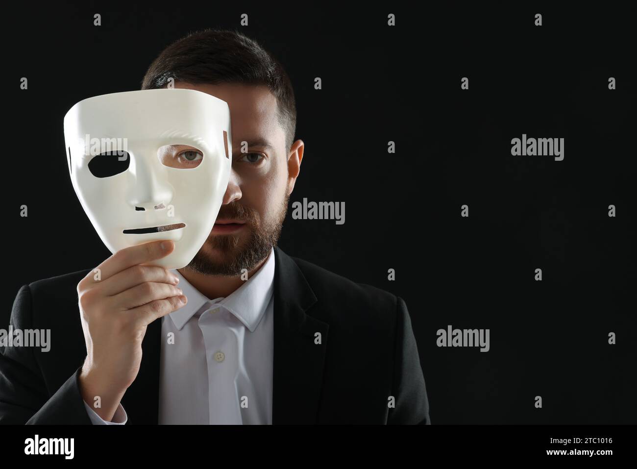 Multiple personality concept. Man covering face with mask on black ...